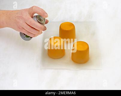 Spraying yellow food colour on small cakes covered with icing Stock ...