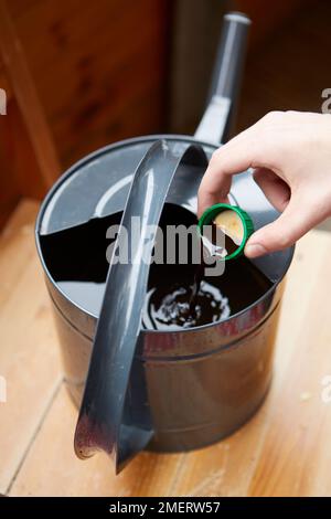 Diluting liquid fertilizer into watering can Stock Photo - Alamy