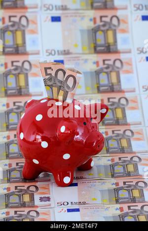 White piggy bank with 50 Euro bills on beige background with copy space ...
