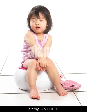 Girl wearing pink vest sitting on a white potty, 20 months Stock Photo - Alamy