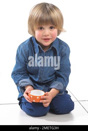 Boy sitting holding small pet feeding bowl, 3 years Stock Photo - Alamy