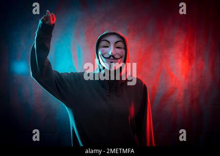 Hacker with anonymous mask with his fist raised in symbol of fight, red ...