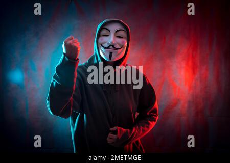 Hacker with anonymous mask with his fist raised in symbol of fight, red ...