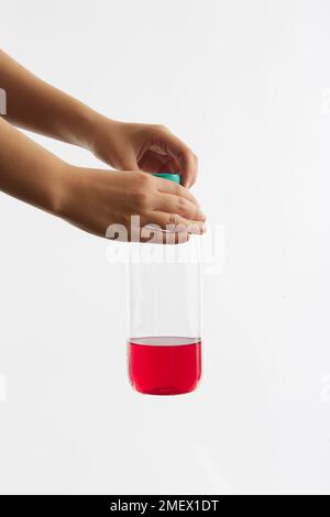 Plastic bottle of red liquid held in two hands Stock Photo - Alamy