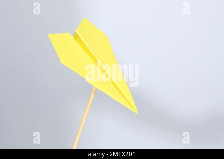 Paper plane made of coloured paper and supported by a wooden stick ...