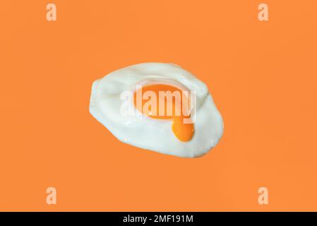 Single vibrant orange egg yolk centered in white ceramic bowl with blue ...
