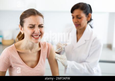 Scared woman getting injection at doctors office Stock Photo - Alamy