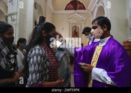 A Catholic priest marks the forehead of a devotee with the symbol of a ...