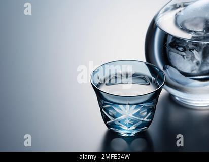 Sake poured into a faceted glass against a black background. The image ...