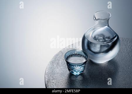 Sake poured into a faceted glass against a black background. The image ...