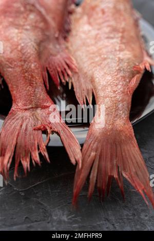 Two frozen headless carcasses of red sea bass Stock Photo - Alamy