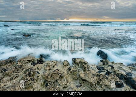 A long exposure shot of a sunrise over the rocky beach in Oahu, Hawaii ...