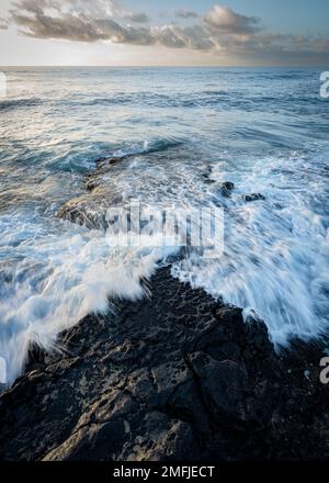 A vertical shot of sunrise over the rocky beach in Oahu, Hawaii Stock ...