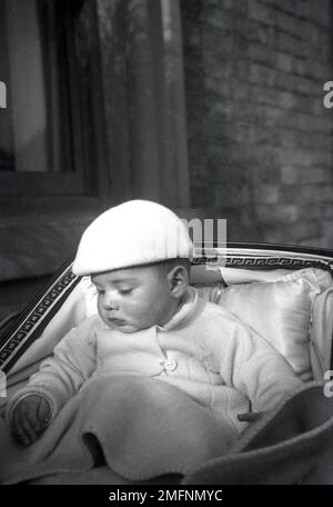 Baby boy legs in black trousers, on white towel cloth, view from above ...