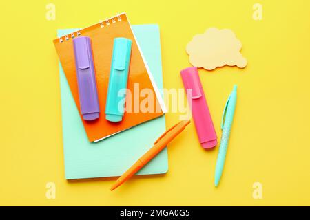 Notebooks, pens, markers and sticky notes on yellow background, closeup ...