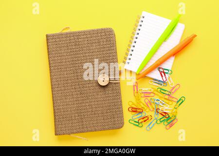 Notebooks, pens and paper clips on yellow background Stock Photo - Alamy