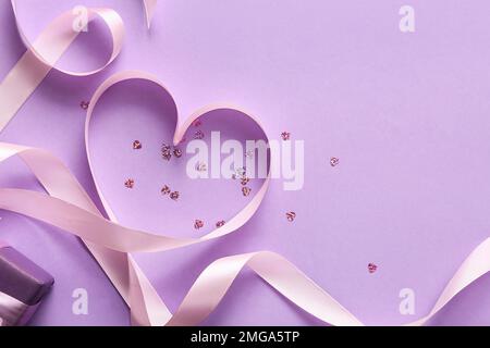 Sequins and heart made of lilac satin ribbon on blue background ...