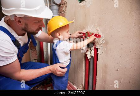 Father and son using spirit level tool while installing plumbing pipes ...