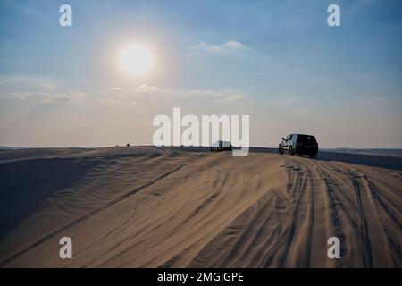 Watching people riding in 4x4's racing over the dunes near Doha, where ...