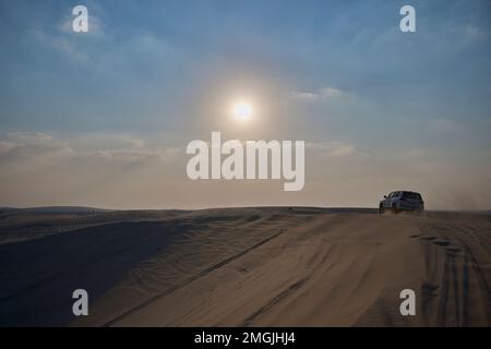 Watching people riding in 4x4's racing over the dunes near Doha, where ...