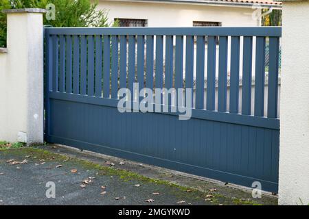 Gray metal driveway entrance gates set in brick fence with lock Stock ...