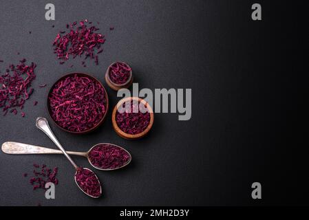 Dried beets in small slices in a wooden bowl on a black concrete ...
