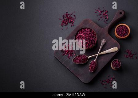 Dried beets in small slices in a wooden bowl on a black concrete ...