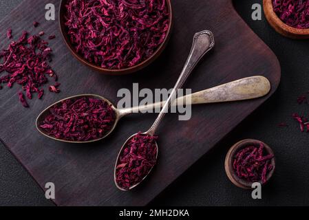 Dried beets in small slices in a wooden bowl on a black concrete ...