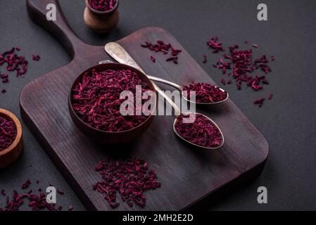 Dried beets in small slices in a wooden bowl on a black concrete ...