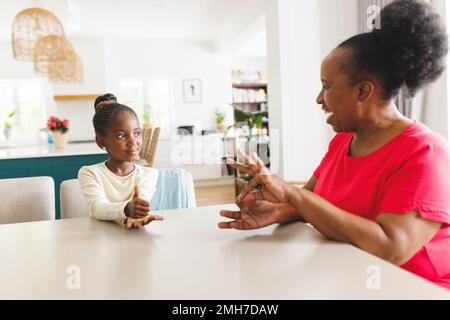 Happy african american grandmother and deaf granddaughter using sign ...