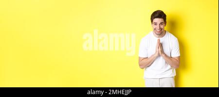 Handsome guy saying thank you, bowing and holding hands in namaste ...