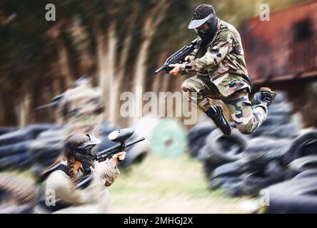 Action, paintball and man shooting and jumping on battlefield with a ...