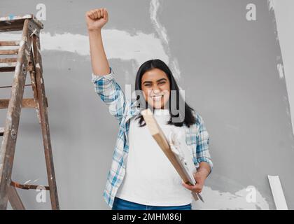 Young Indian woman raises fist proud of DIY construction progress carry ...