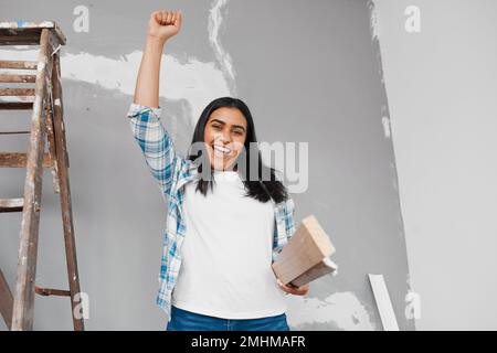 Young Indian woman raises fist proud of DIY construction progress carry ...
