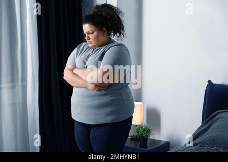 Overweight woman suffering from depression at home and word STRESS ...