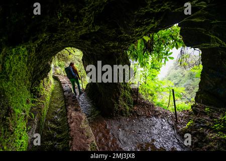 Hiker in a tunnel at PR9 Levada do Caldeirao Verde, Madeira, Portugal ...