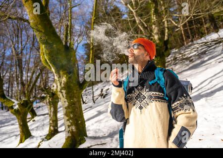 A man smoking a cigarette on a snowy hill in winter, enjoying the cold ...