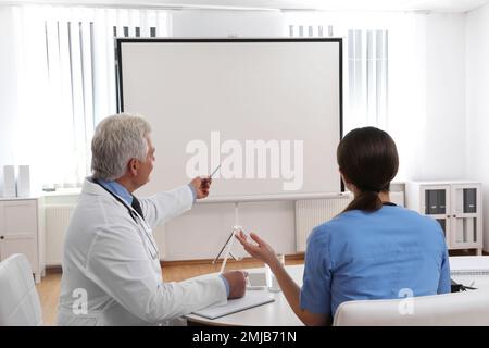 Team of doctors looking at projection screen indoors Stock Photo - Alamy