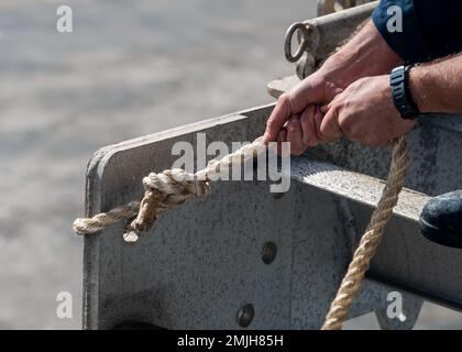 A U.S. Navy Seaman Apprentice heaves a line from guided-missile frigate ...
