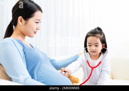 The little girl to listen to the fetus Stock Photo - Alamy