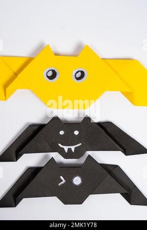 Halloween origami - yellow paper bat with eyes and teeth on a white ...