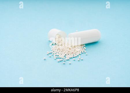 Gel capsule opened. White medicine powder spilled out on light blue ...