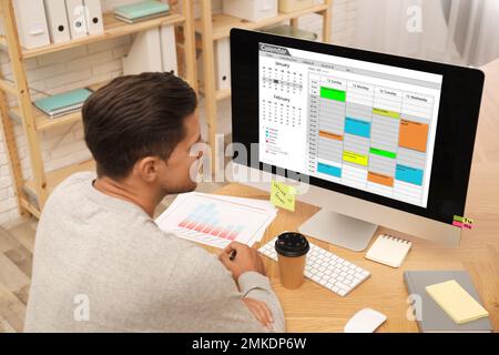 Handsome man using calendar app on computer in office Stock Photo - Alamy