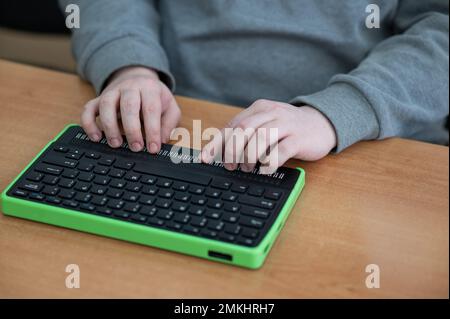 A blind man uses a computer with a Braille display and a computer ...