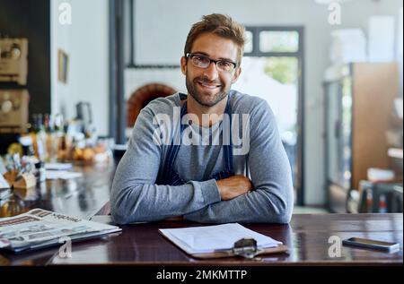 It pays to work hard. a handsome young coffee shop owner doing some ...