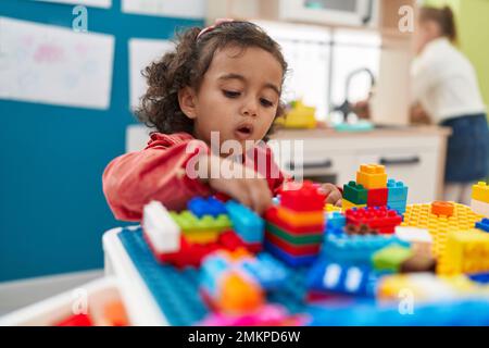 Adorable hispanic girl playing with construction blocks sitting on ...