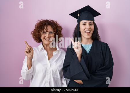 Hispanic mother and daughter wearing graduation cap and ceremony robe ...