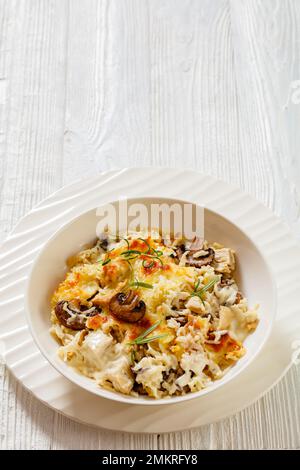 Cheesy Chicken Mushroom Rice Casserole in white bowl, vertical view ...