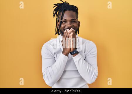 African man with dreadlocks wearing turtleneck sweater over yellow ...