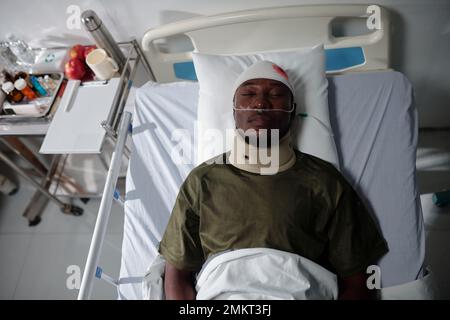 Sick military man with bleeding head injury lying on bed in hospital ...